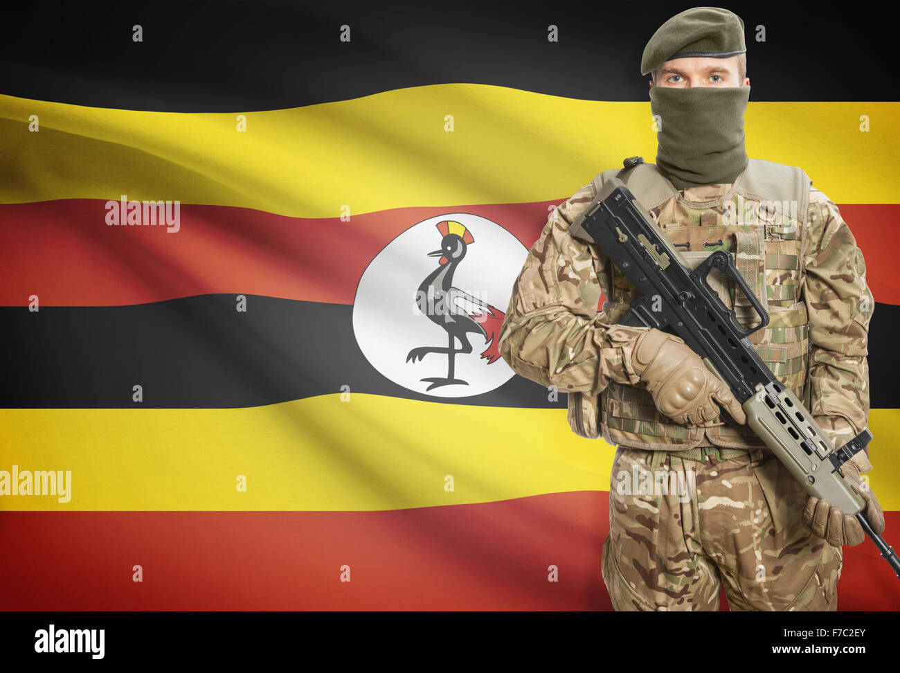 Soldier holding machine gun with national flag on background - Uganda ...