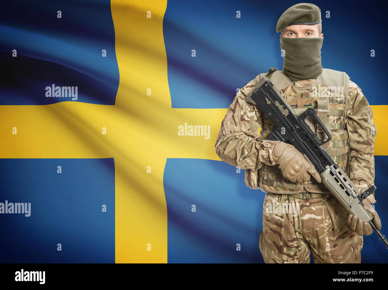 Soldier holding machine gun with national flag on background - Sweden ...
