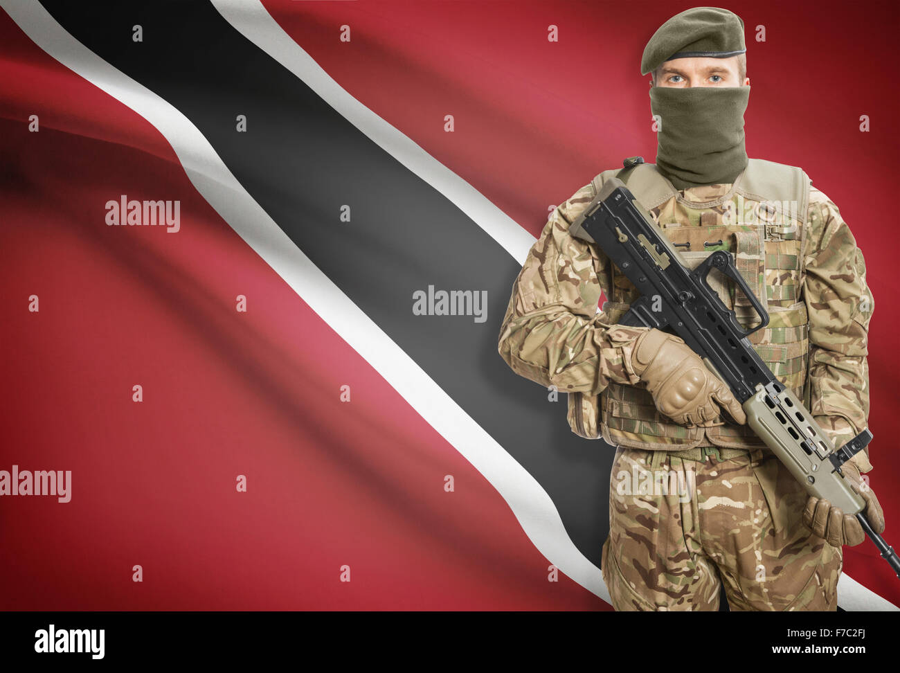 Soldier holding machine gun with national flag on background - Trinidad ...