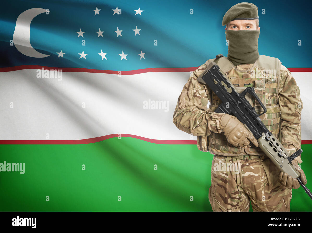 Soldier holding machine gun with national flag on background ...