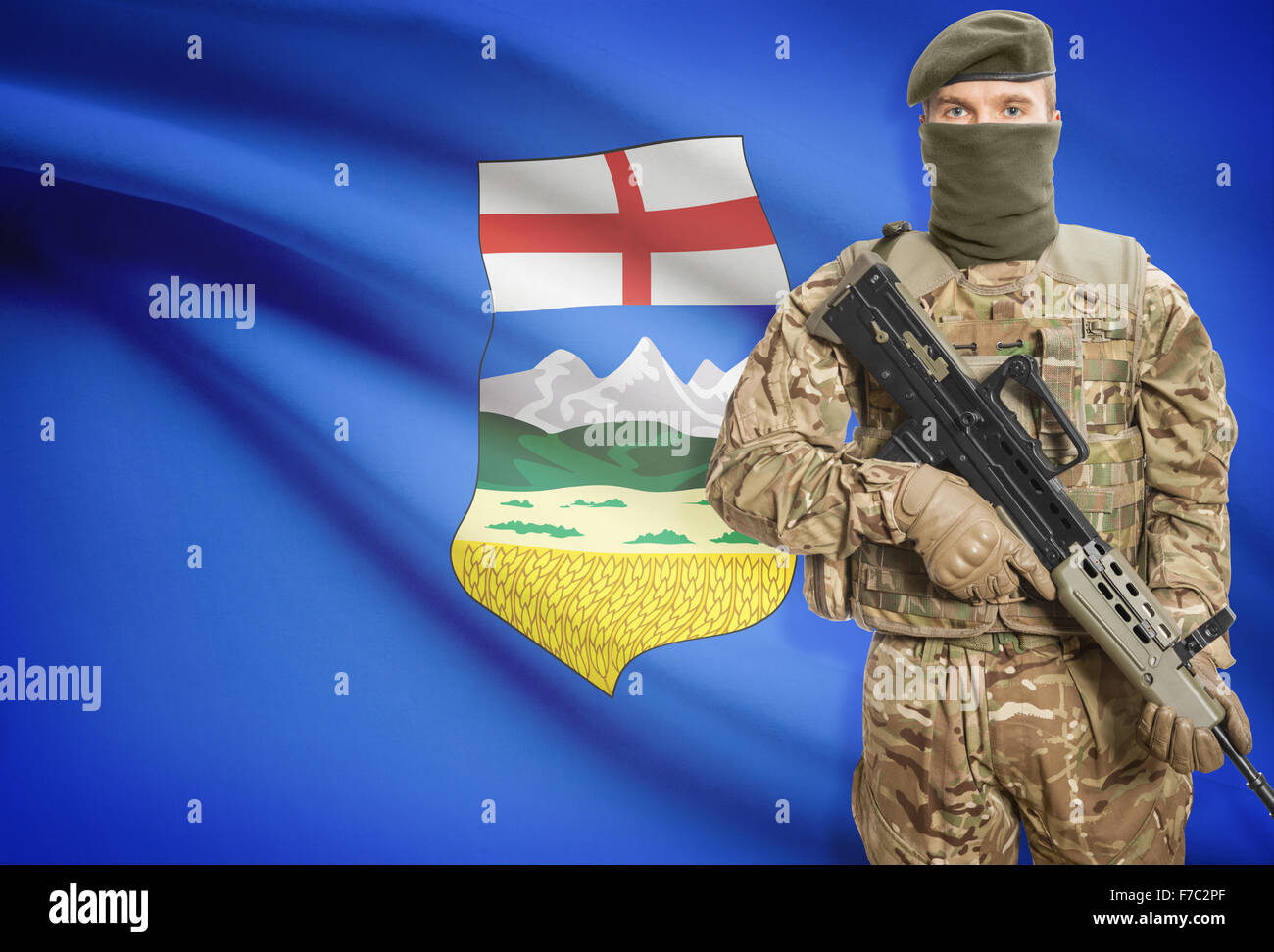 Soldier holding machine gun with Canadian province flag on background ...