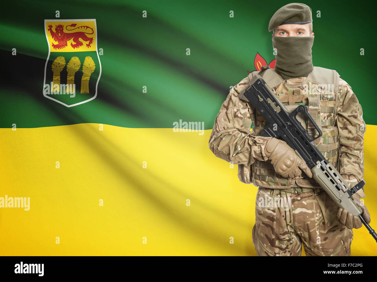 Soldier holding machine gun with Canadian province flag on background ...