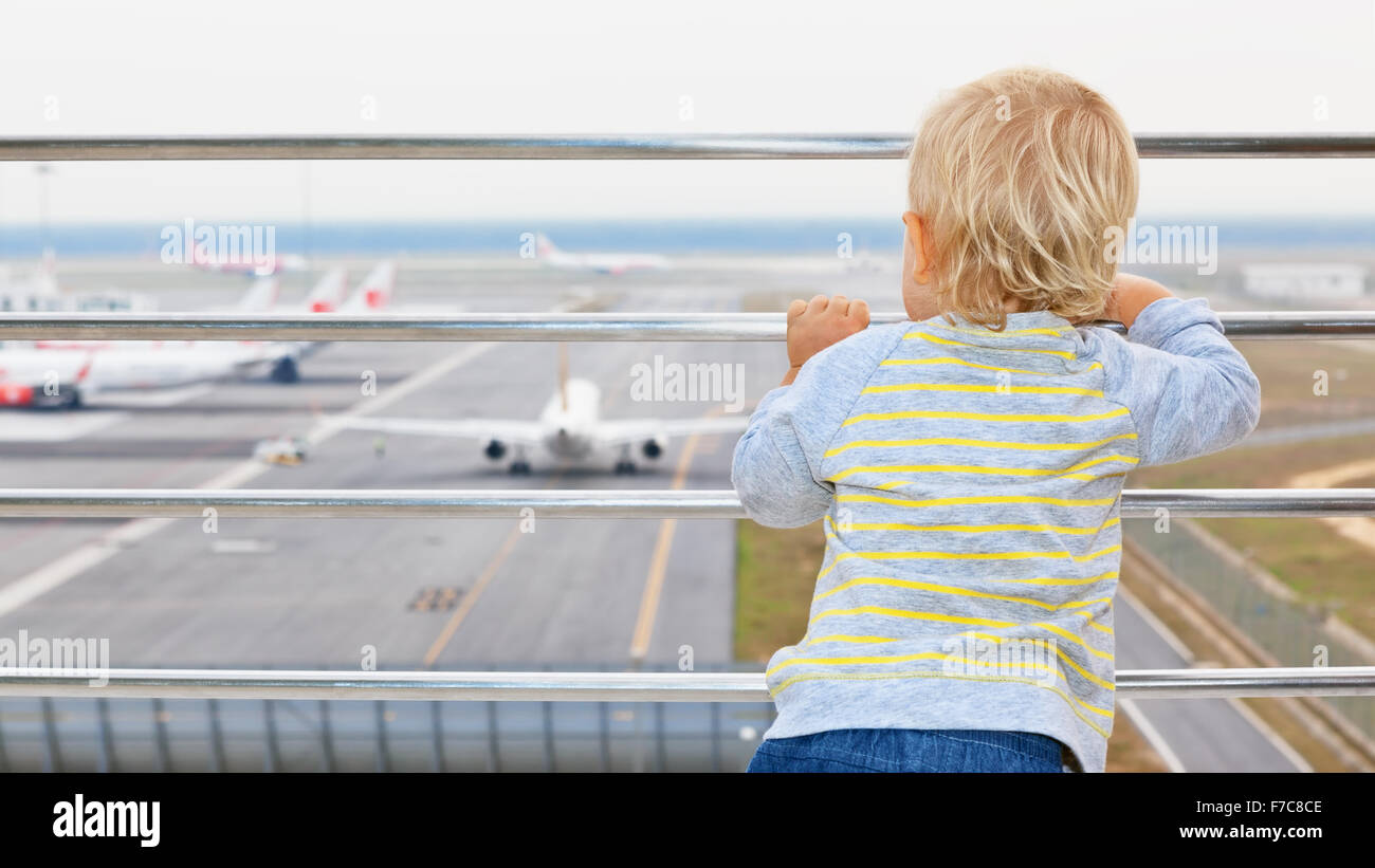 Little baby boy waiting for boarding to flight in airport transit hall ...