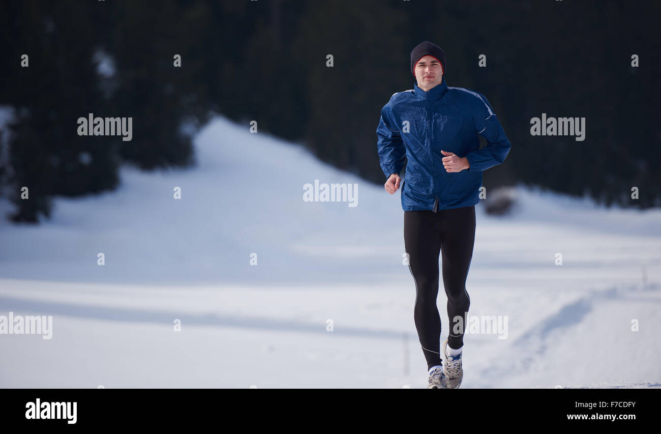young man jogging on snow in forest, bautiful sunny winter day ...