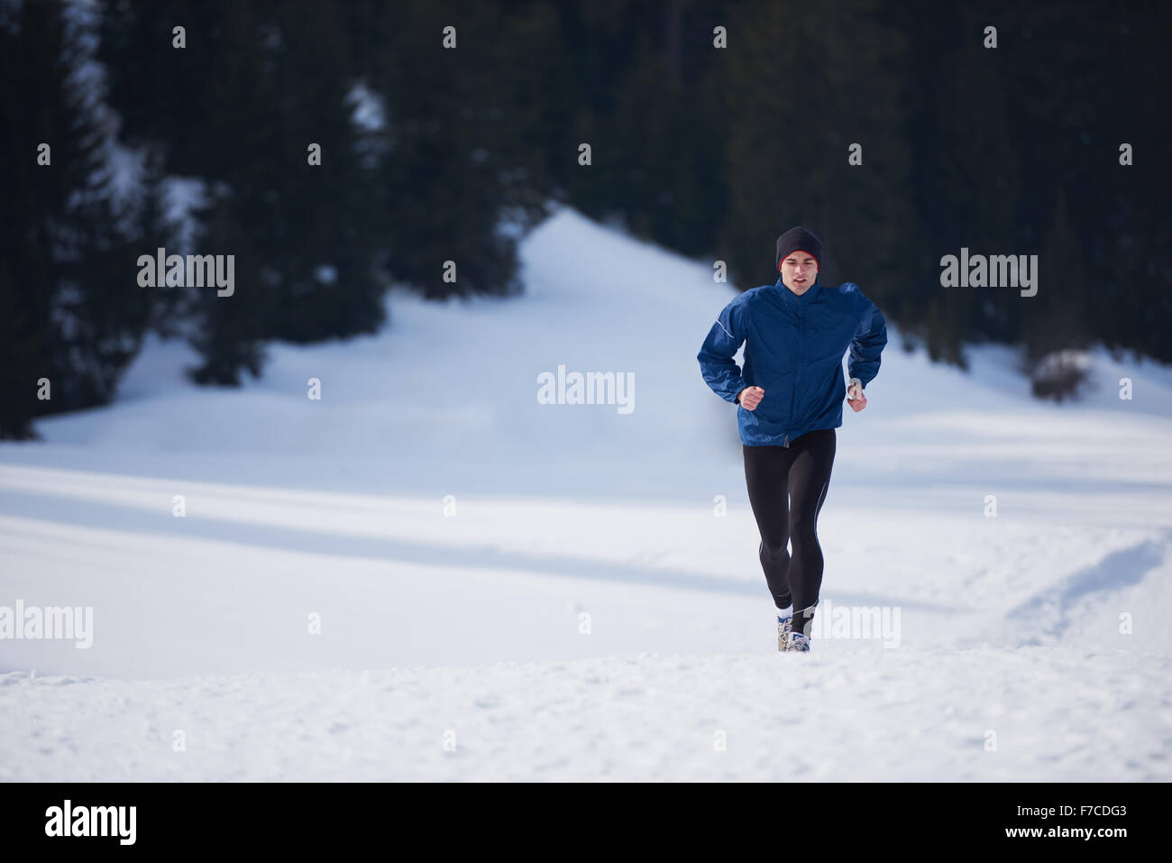 young man jogging on snow in forest, bautiful sunny winter day ...