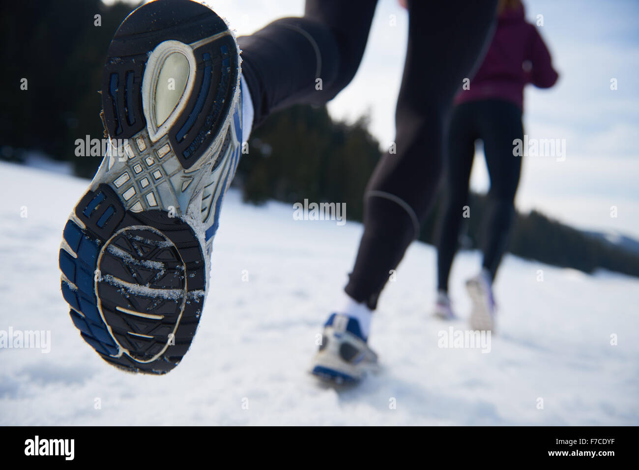 healthy young couple jogging outside on snow in forest. athlete running ...