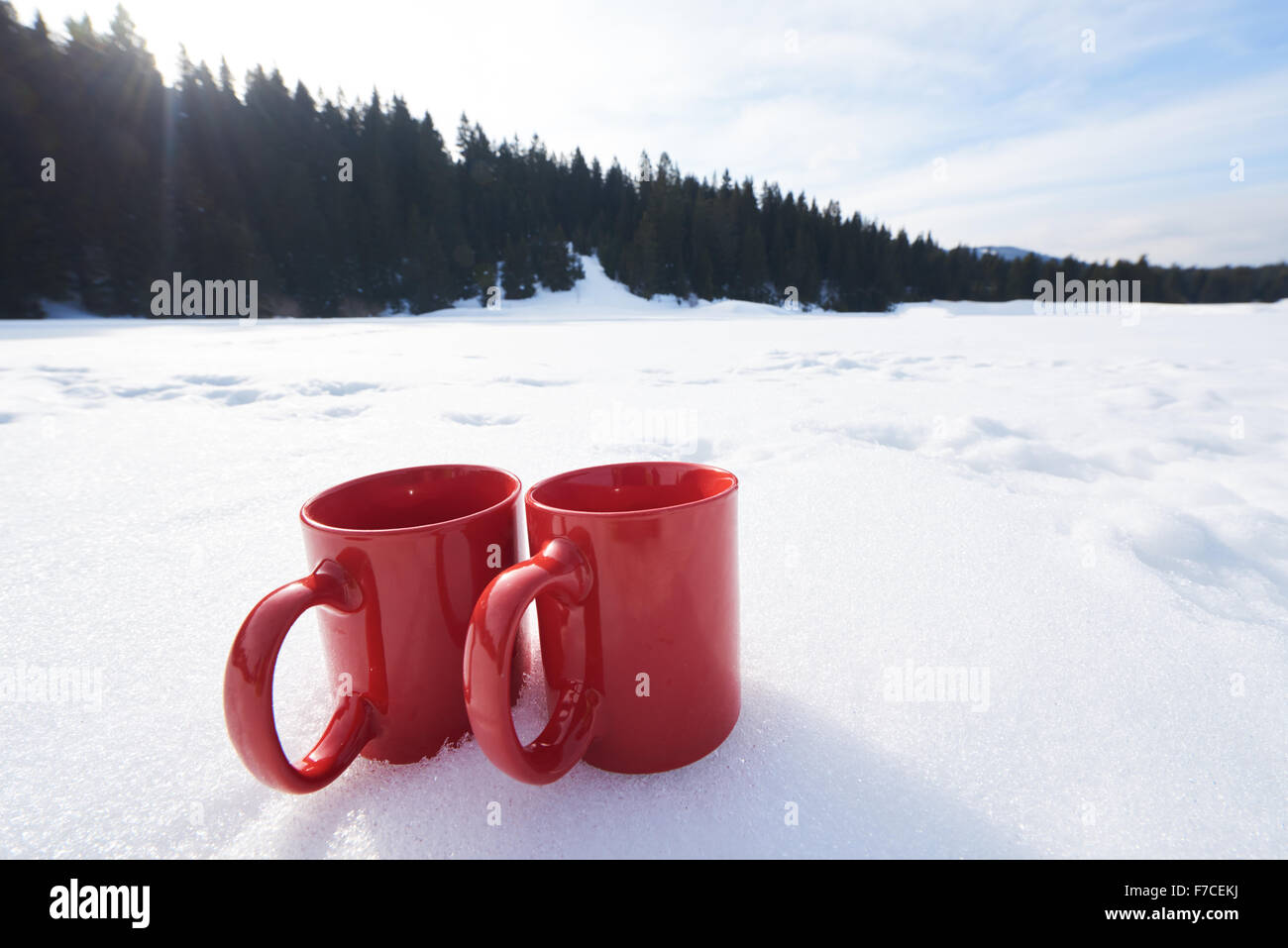 two red coups of hot tea drink in snow at beautiful winter sunny day ...