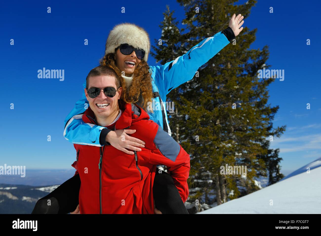 Happy young couple has fun on fresh snow at beautiful winter sunny day ...
