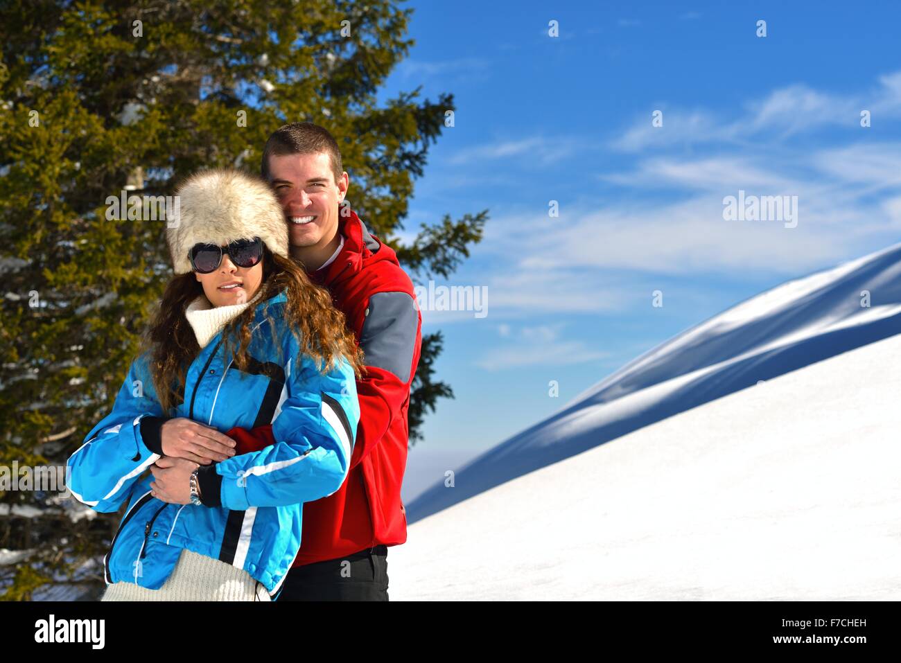 Happy young couple has fun on fresh snow at beautiful winter sunny day ...