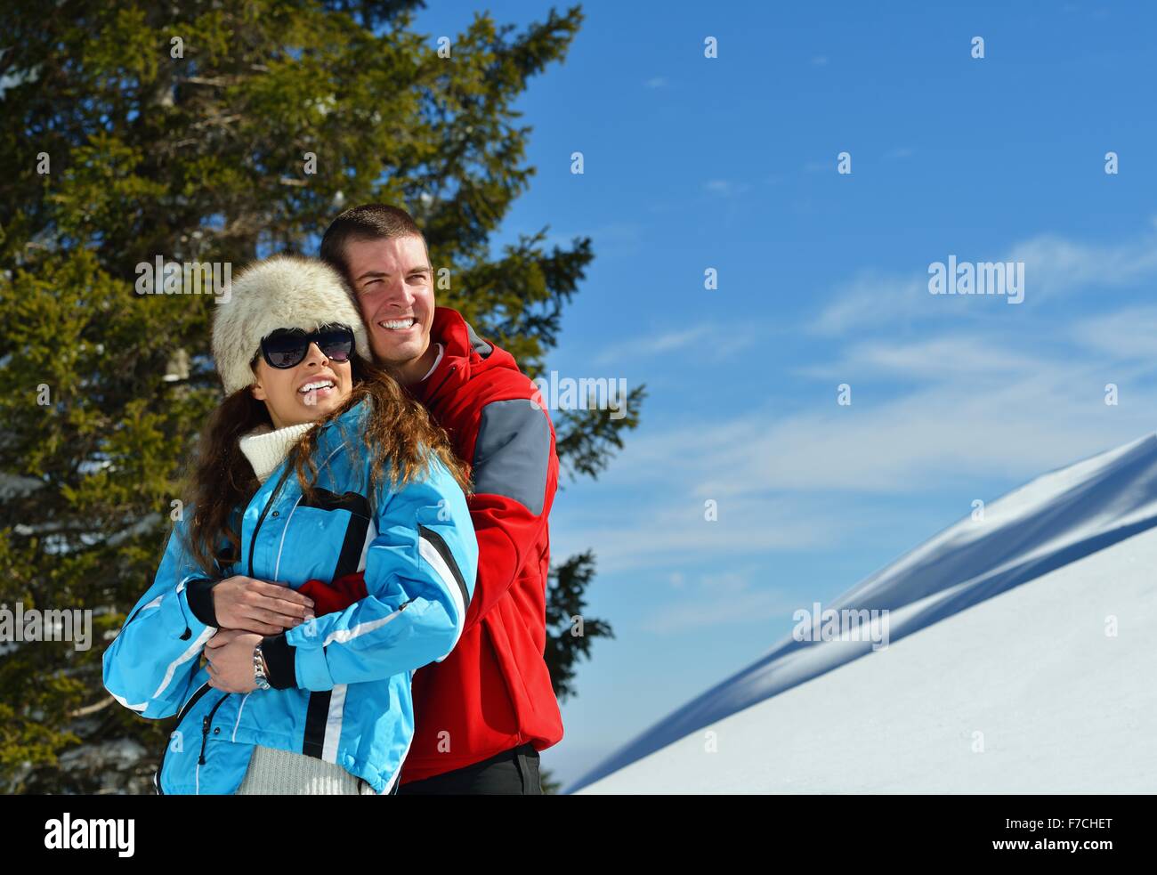 Happy young couple has fun on fresh snow at beautiful winter sunny day ...