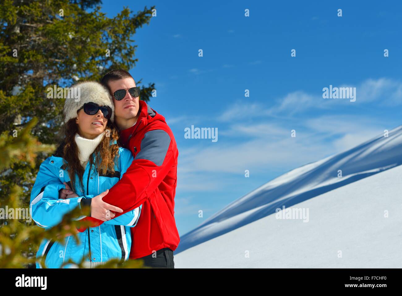 Happy young couple has fun on fresh snow at beautiful winter sunny day ...
