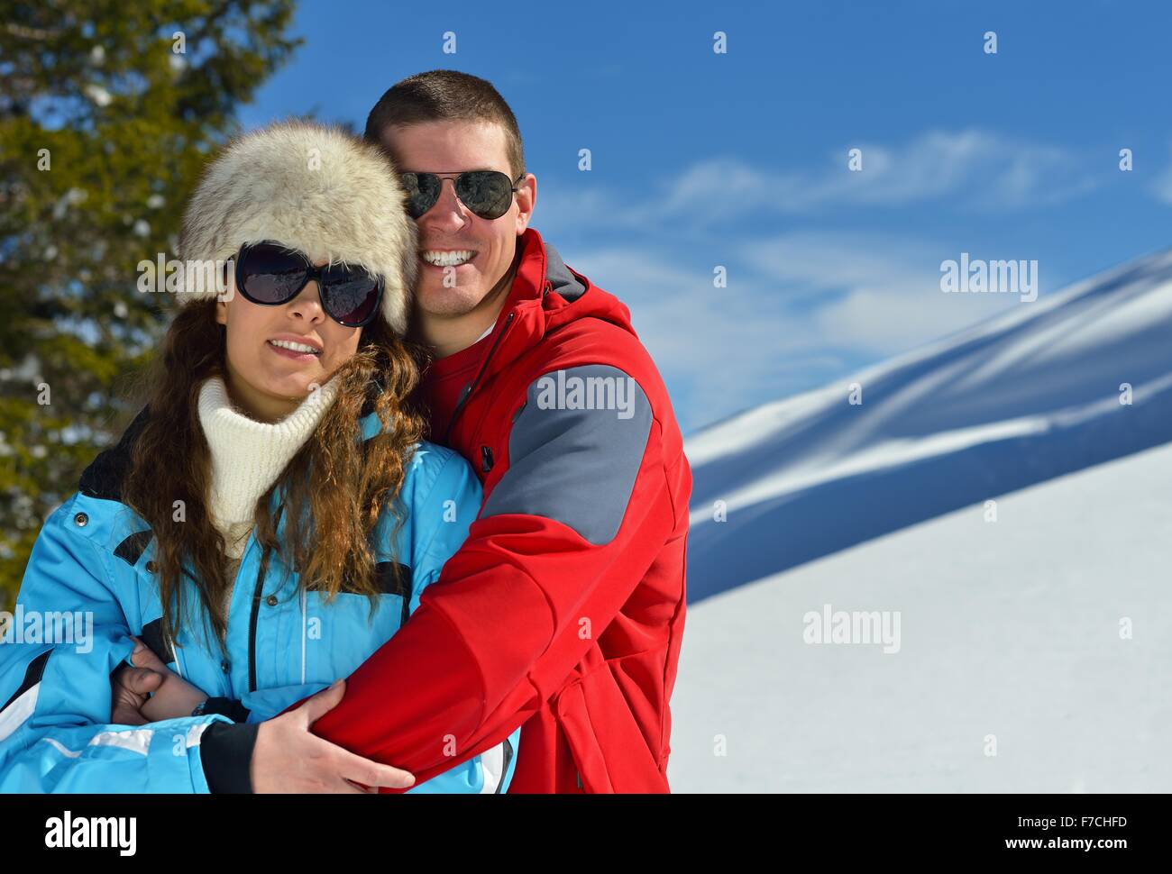Happy young couple has fun on fresh snow at beautiful winter sunny day ...