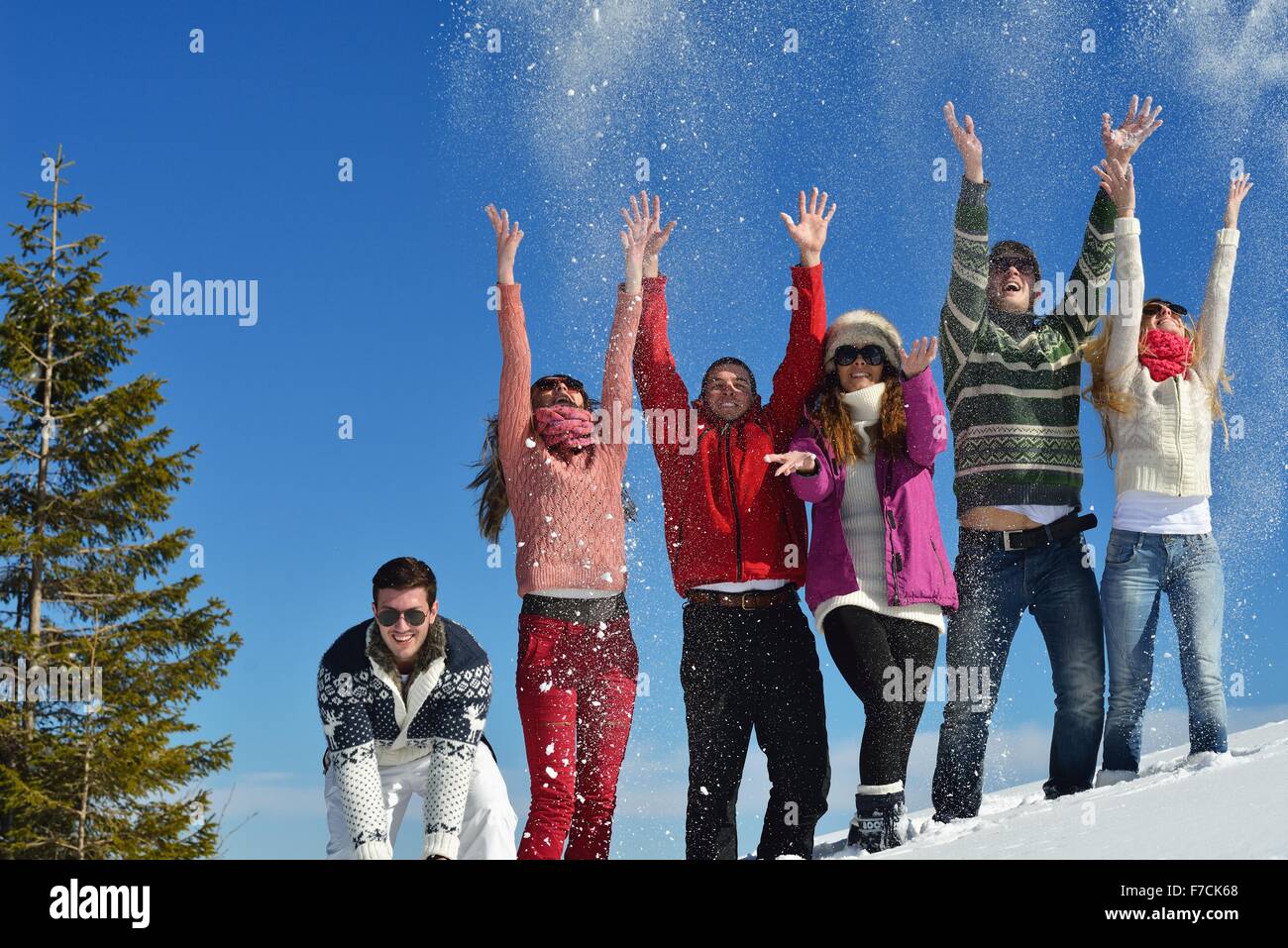 happy young people group have fun and enjoy fresh snow at beautiful ...