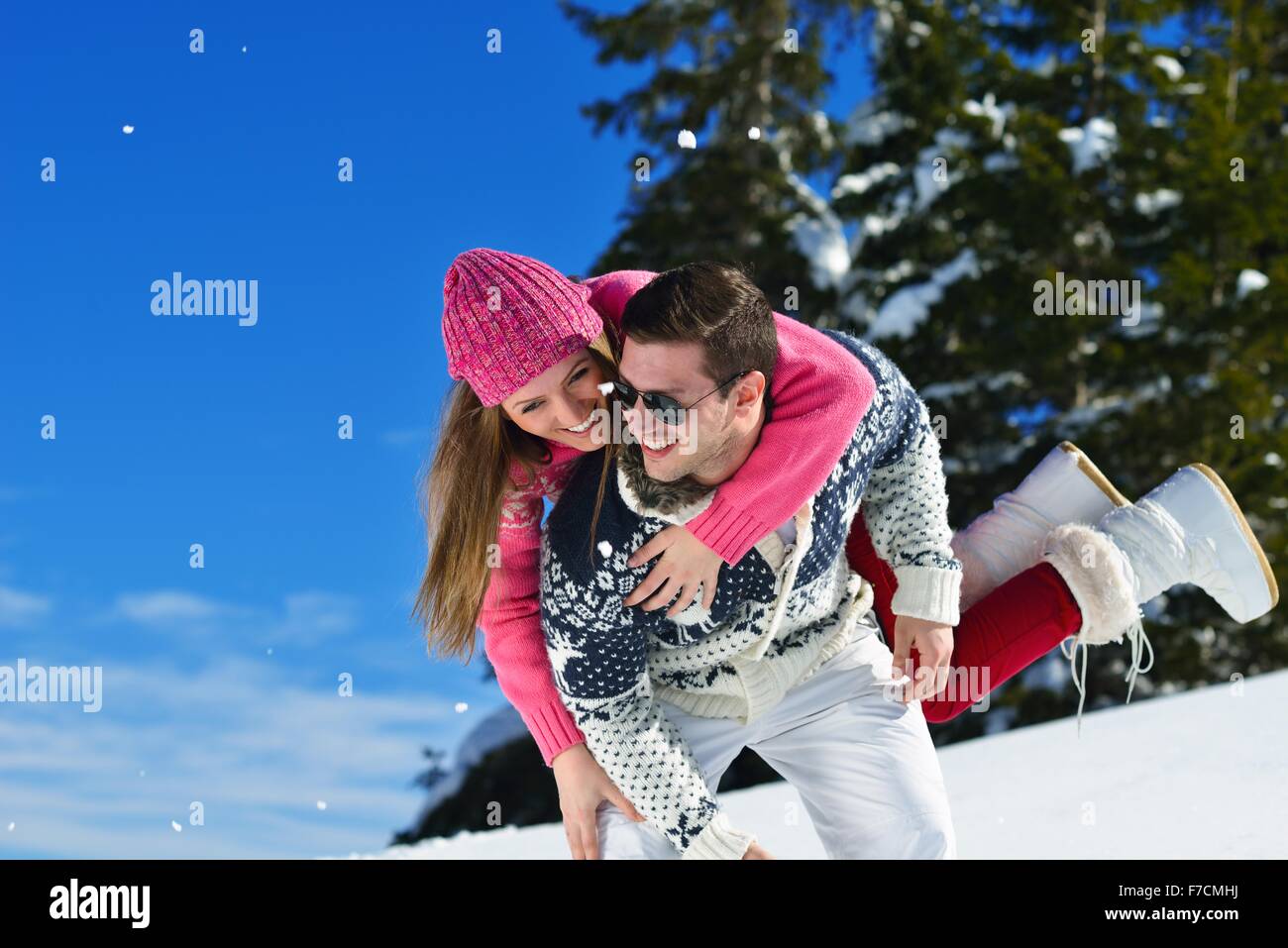 Happy young couple has fun on fresh snow at beautiful winter sunny day ...