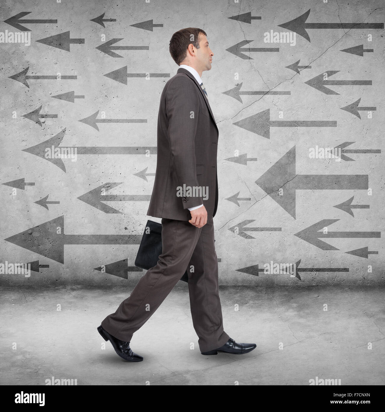 Businessman walking against arrows Stock Photo - Alamy
