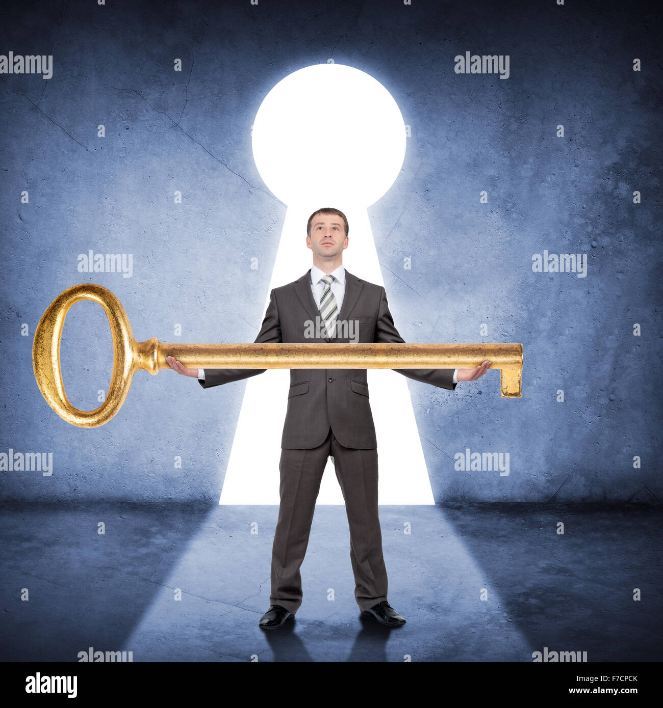 Man in suit holding huge gold key Stock Photo - Alamy