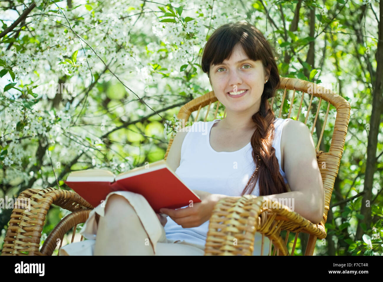 Relaxing girl in rocking-chair against bloom garden Stock Photo - Alamy