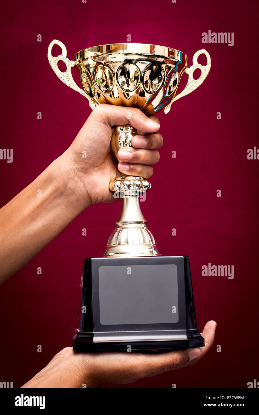 hand holding up a gold trophy cup as a winner in a competition Stock ...