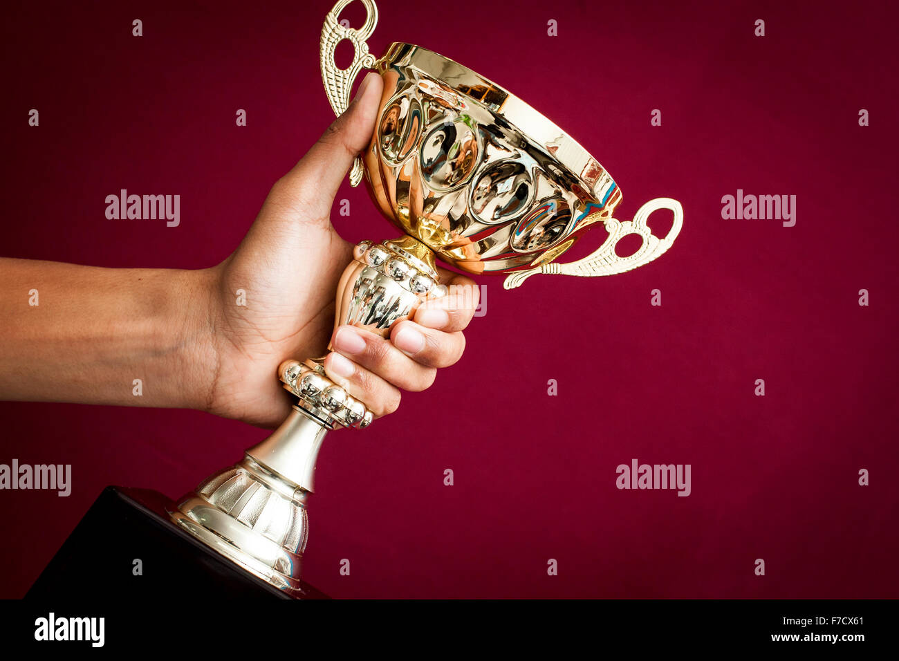 Hand holding up gold trophy hi-res stock photography and images - Alamy