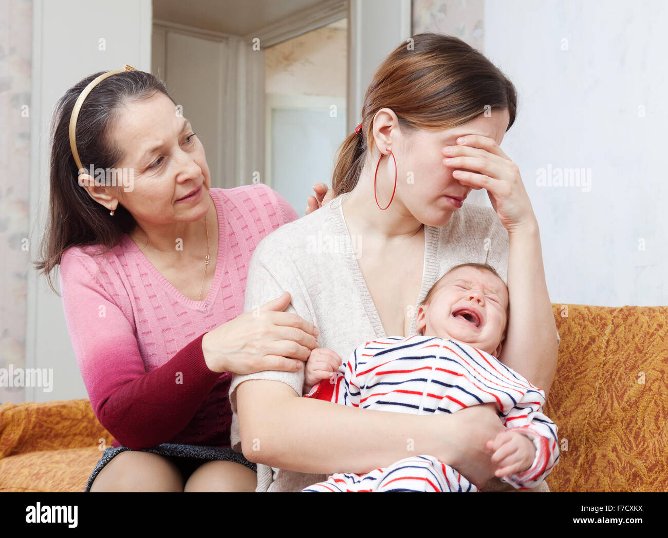 Mature woman gives solace to crying adult daughter with baby at home ...