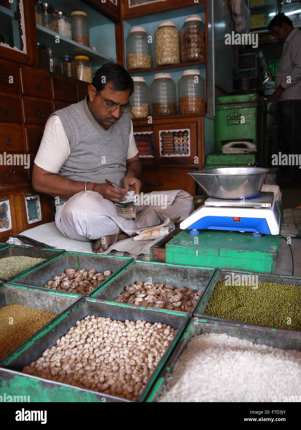 Dried food trader concentrates on paperwork whilst sitting cross legged ...