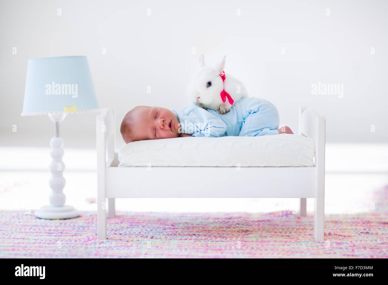 Adorable new born kid sleeping in a white toy bed with real rabbit ...