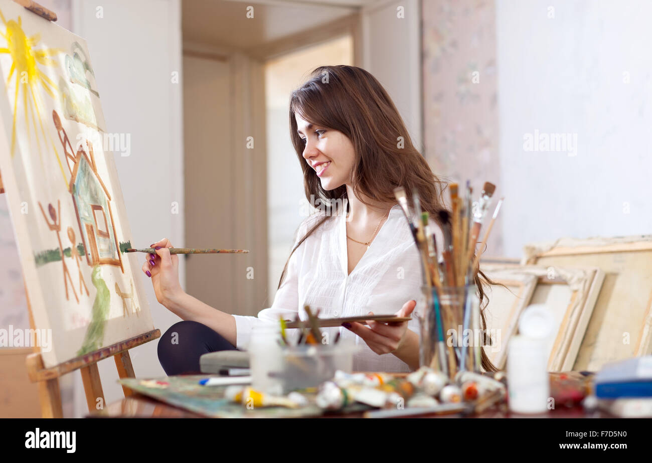 Smiling female artist paints picture on canvas with oil paints Stock ...