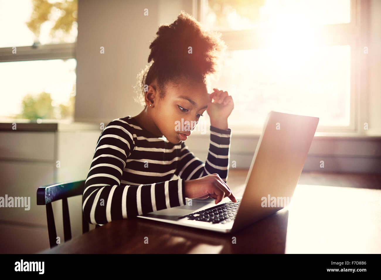 Young girl sitting at the dining table at home working on her homework ...