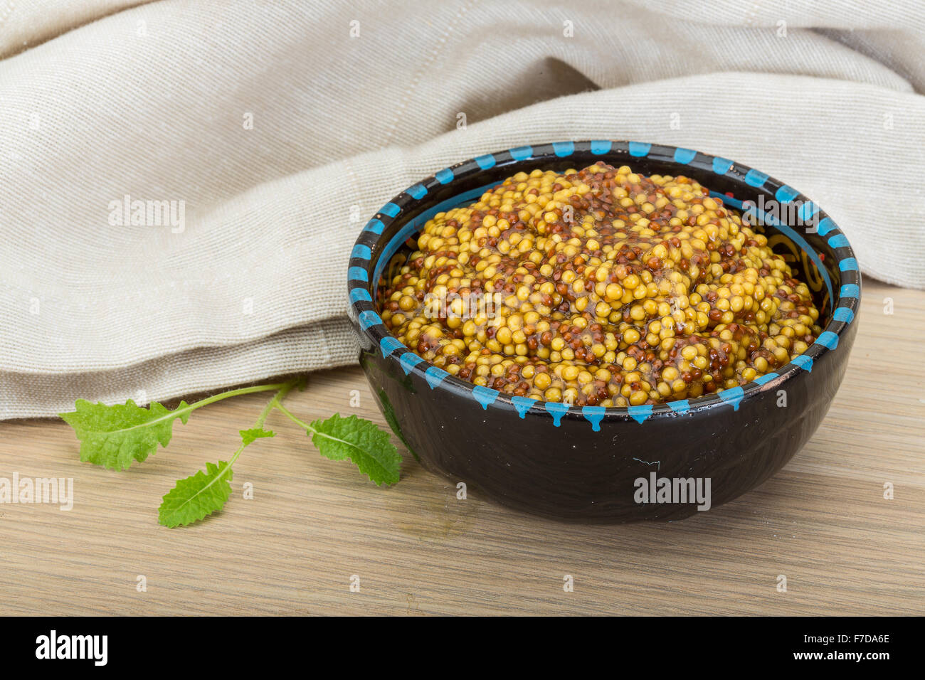French mustard with fresh leaves on wooden background Stock Photo - Alamy