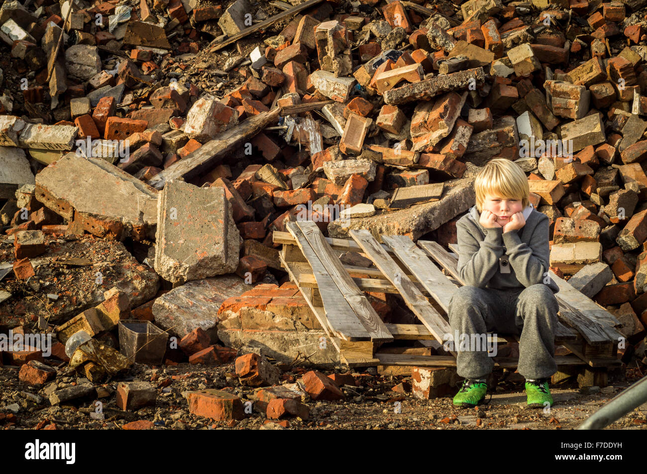 A bored boy sat amongst brick rubble Stock Photo - Alamy
