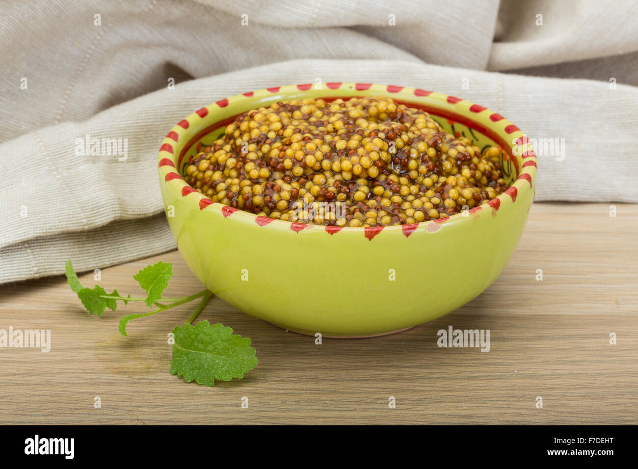 French mustard with fresh leaves on wooden background Stock Photo - Alamy