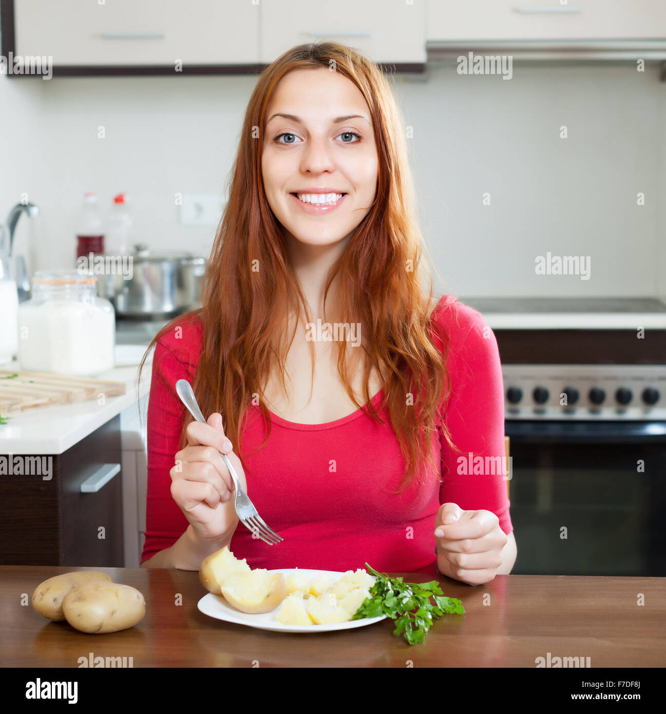 Happy woman eating jacket potatoes at home interior Stock Photo - Alamy