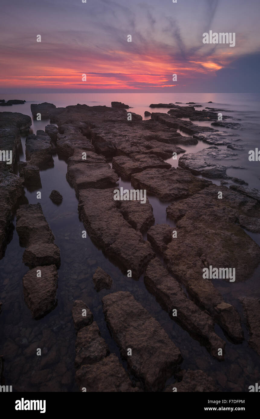 Sunset Over the Sea with Rocks in Foreground Stock Photo - Alamy