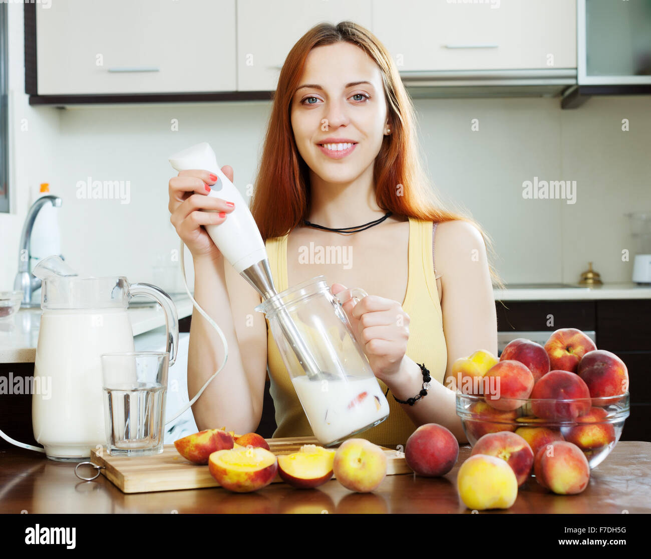 cheerful long-haired woman cooking dairy beverages with electric ...