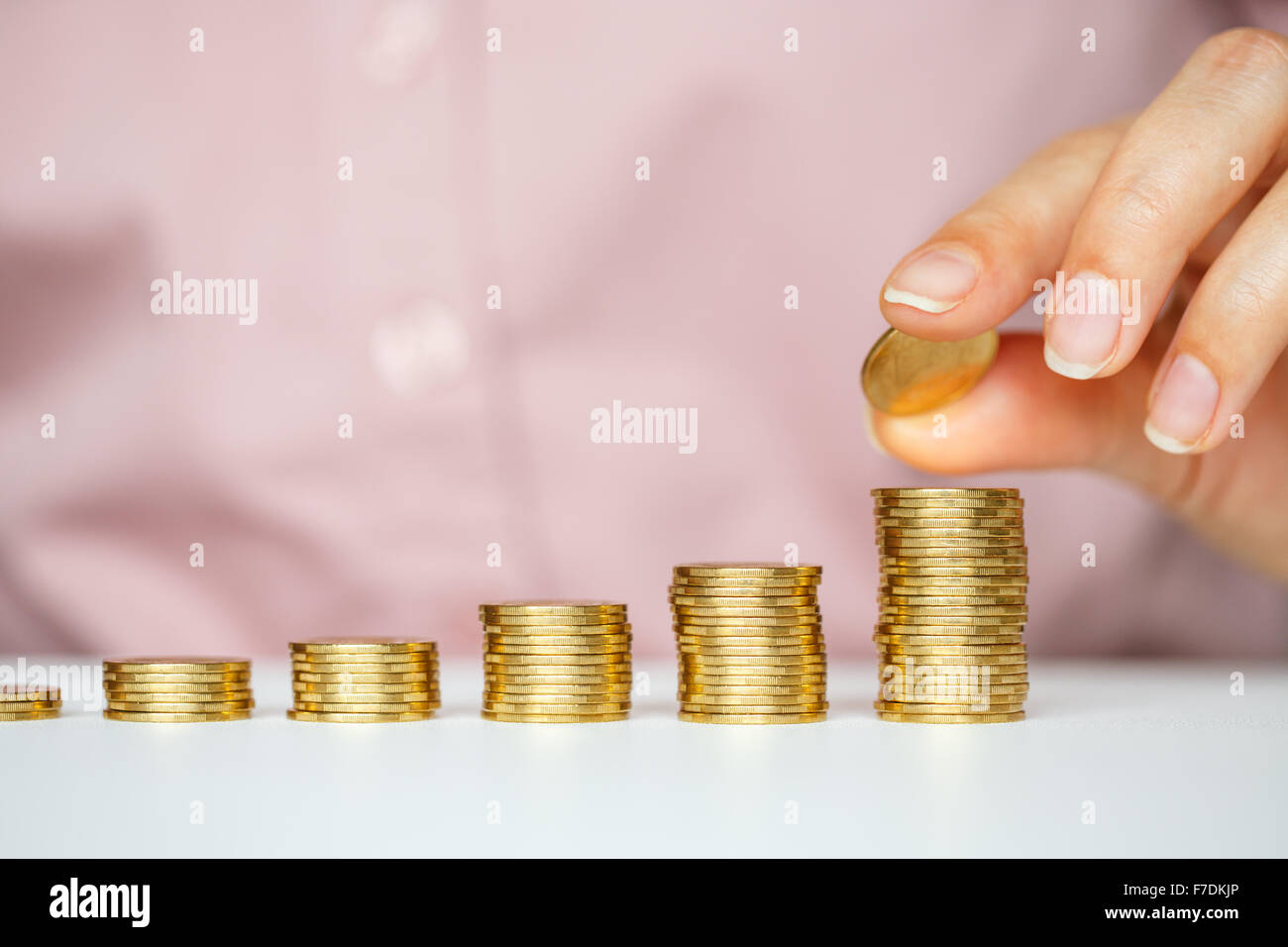 Savings, female hand stacking gold coins into increasing columns Stock ...