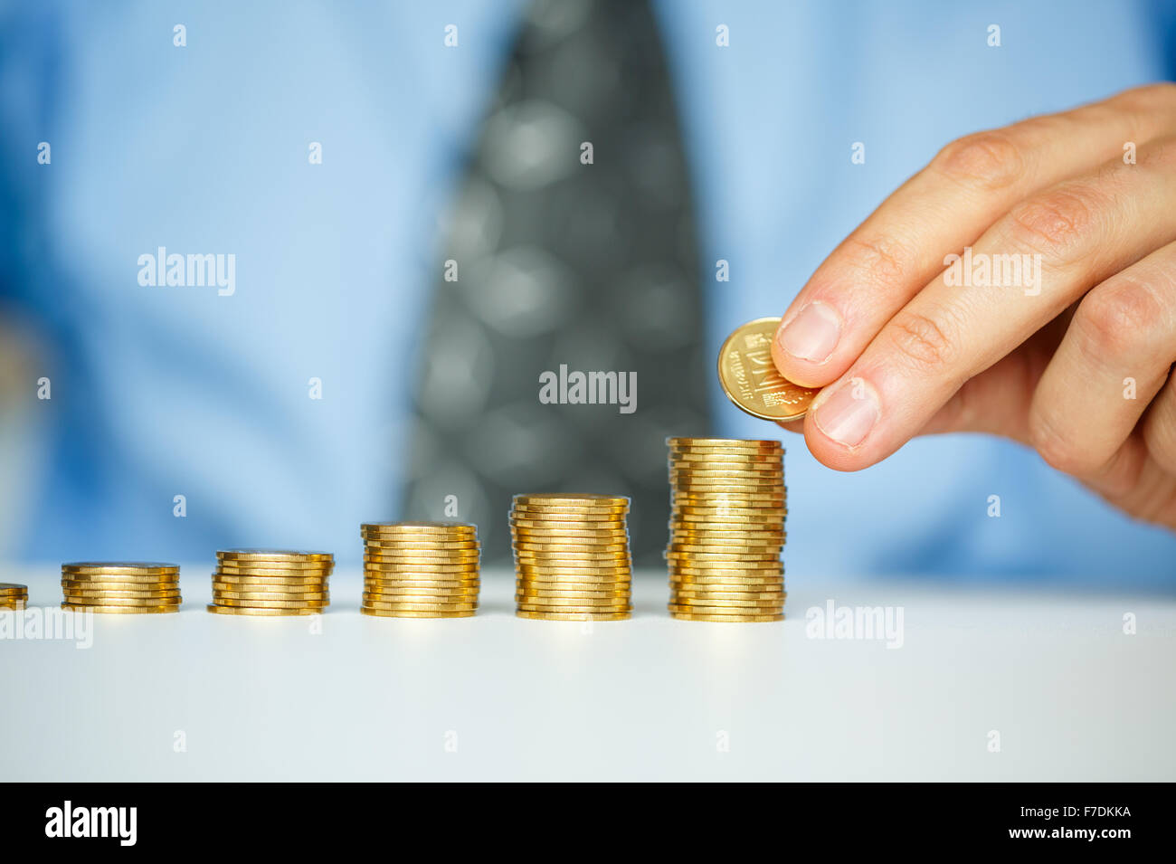 Savings, male hand stacking gold coins into increasing columns Stock ...