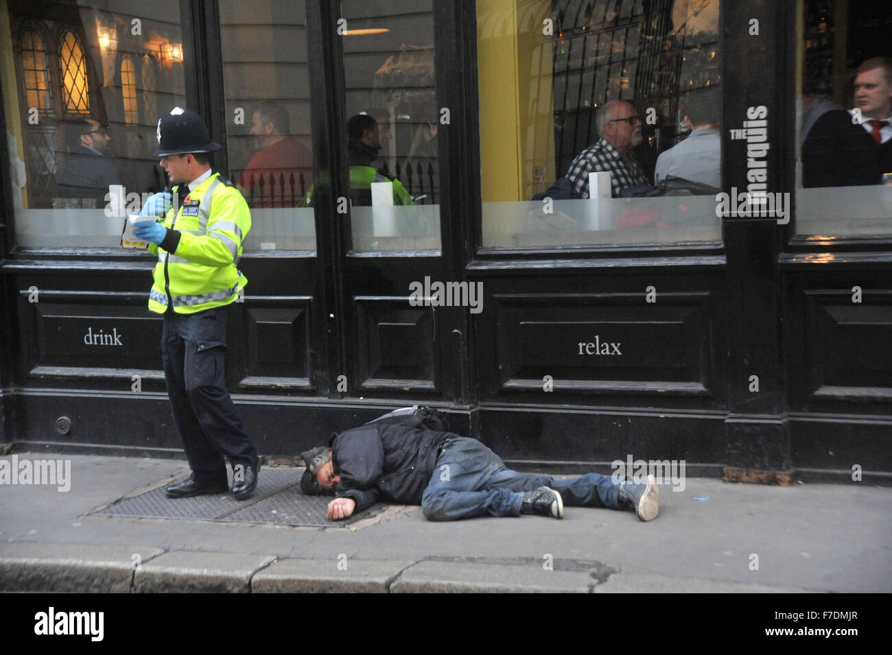 London, UK, 30 October 2015, a policeman calls for assistance for a man ...