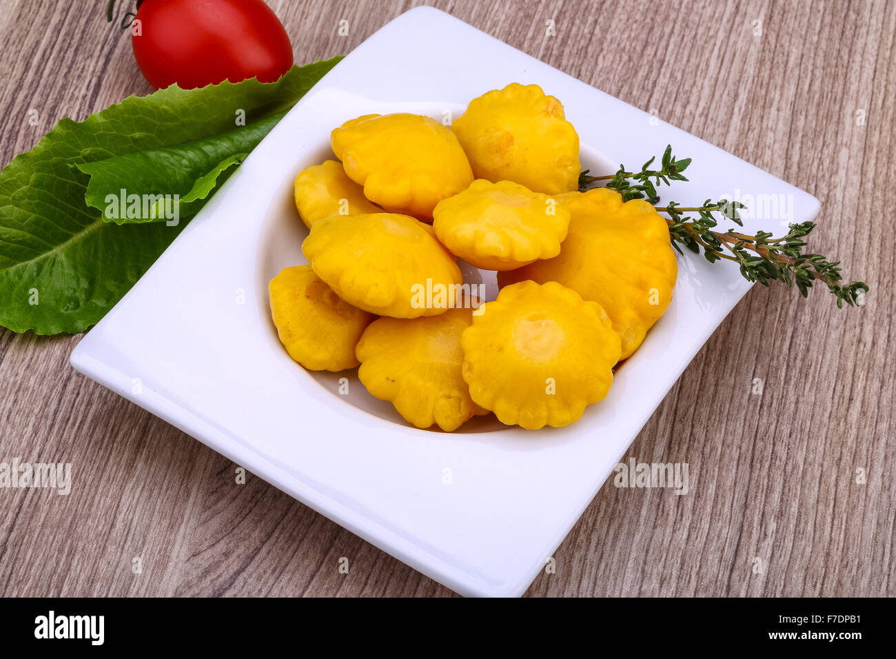 Yellow Pickled patissons with thyme leaves on the wood background Stock ...