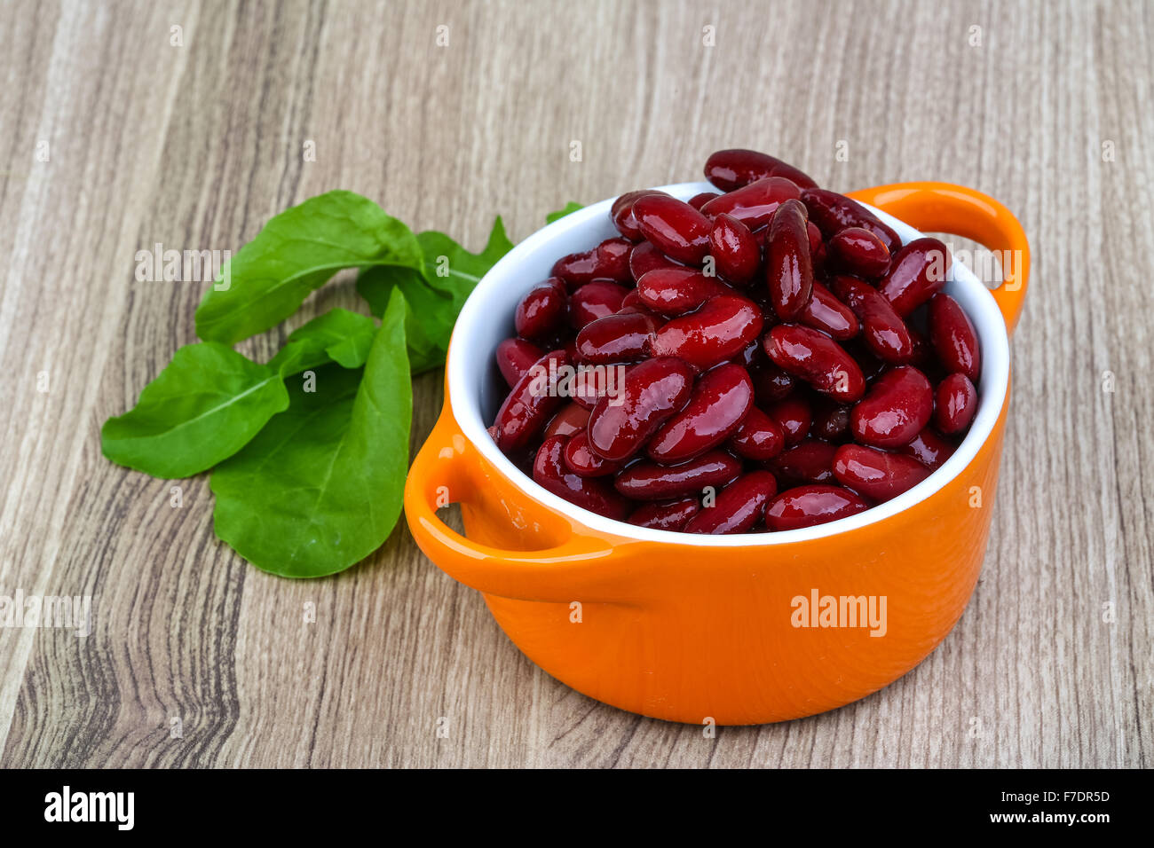 Red kidney on the bowl with ruccola leaves wood background Stock Photo ...