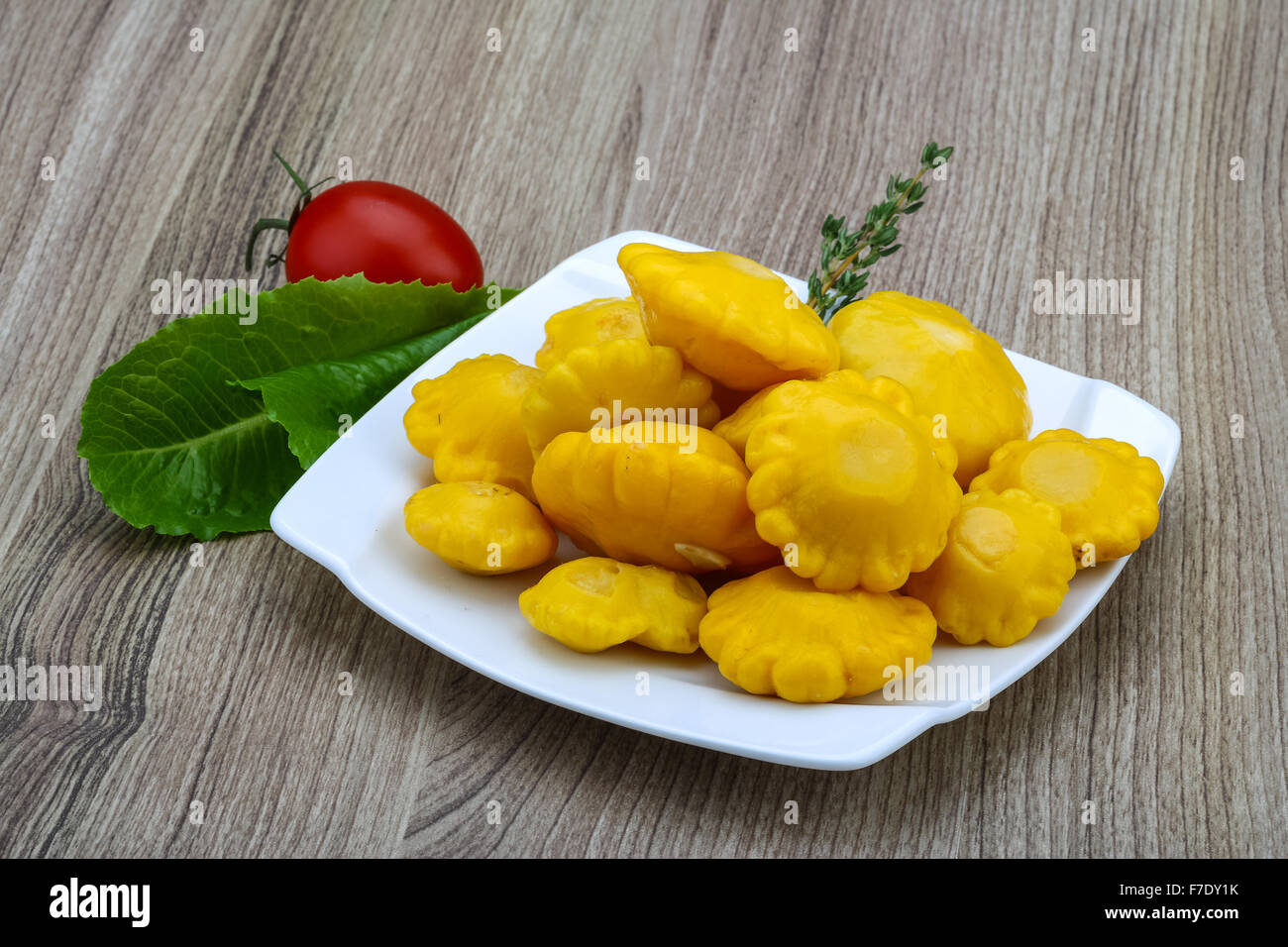 Yellow Pickled patissons with thyme leaves on the wood background Stock ...