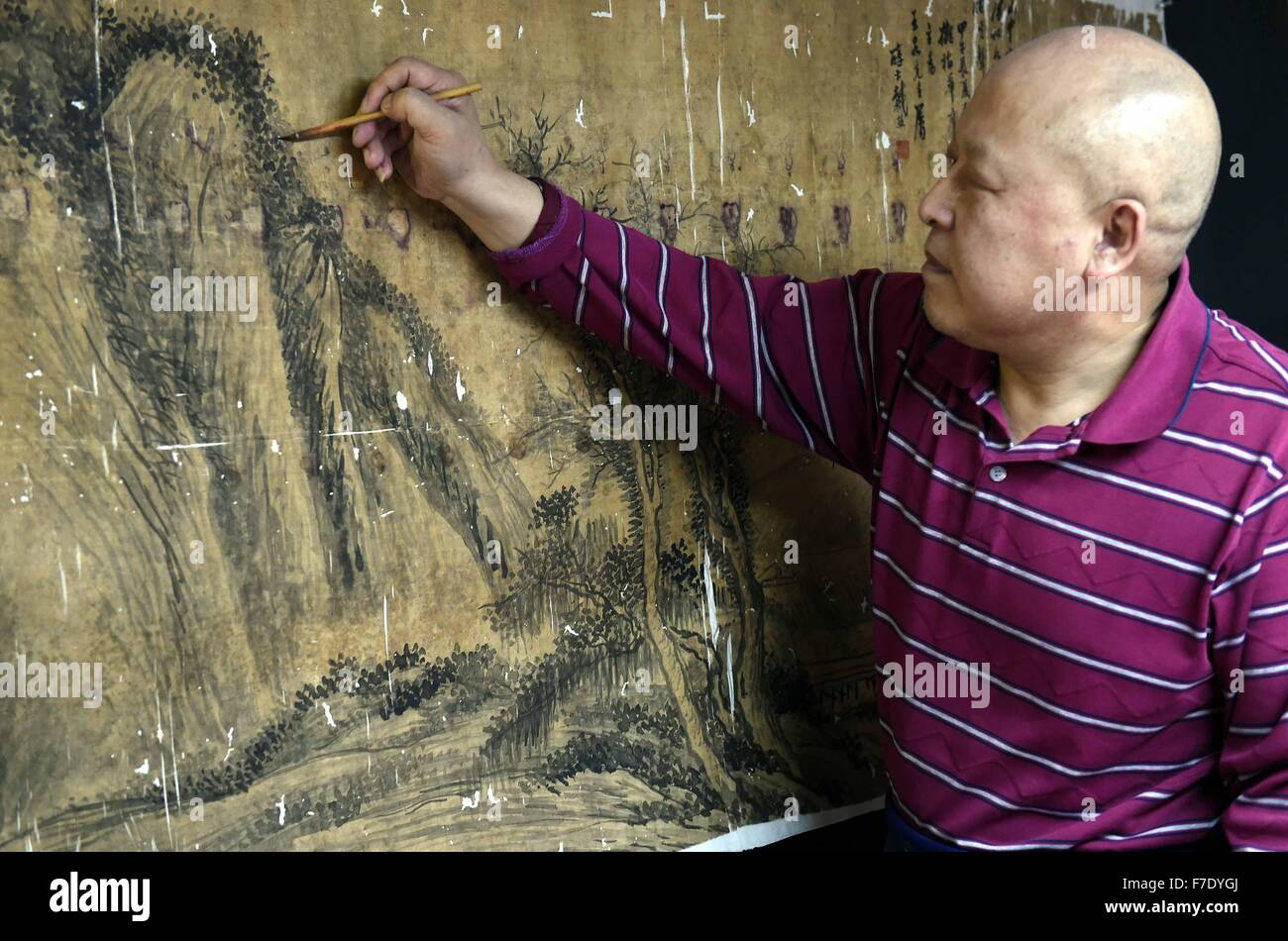 Beijing, China. 29th Nov, 2015. Artist Wang Yuwei colours an ancient ...