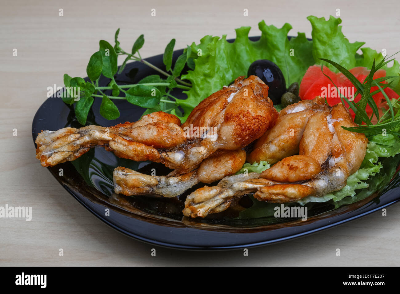 Fried frog legs with olive, herbs and spices Stock Photo - Alamy