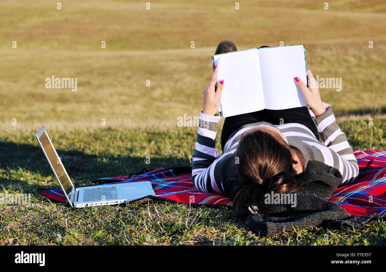 young teen girl read book and study homework outdoor in nature with ...