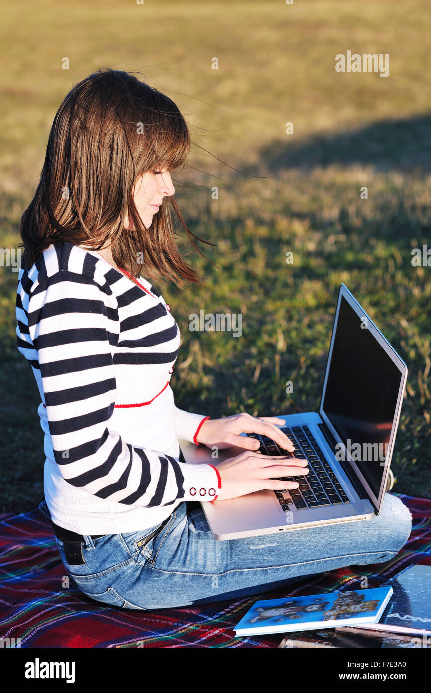 young teen woman work on laptop computer outdoor in nature with blue ...