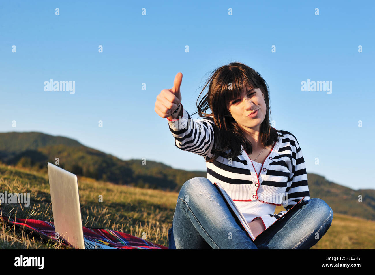 young teen woman work on laptop computer outdoor in nature with blue ...