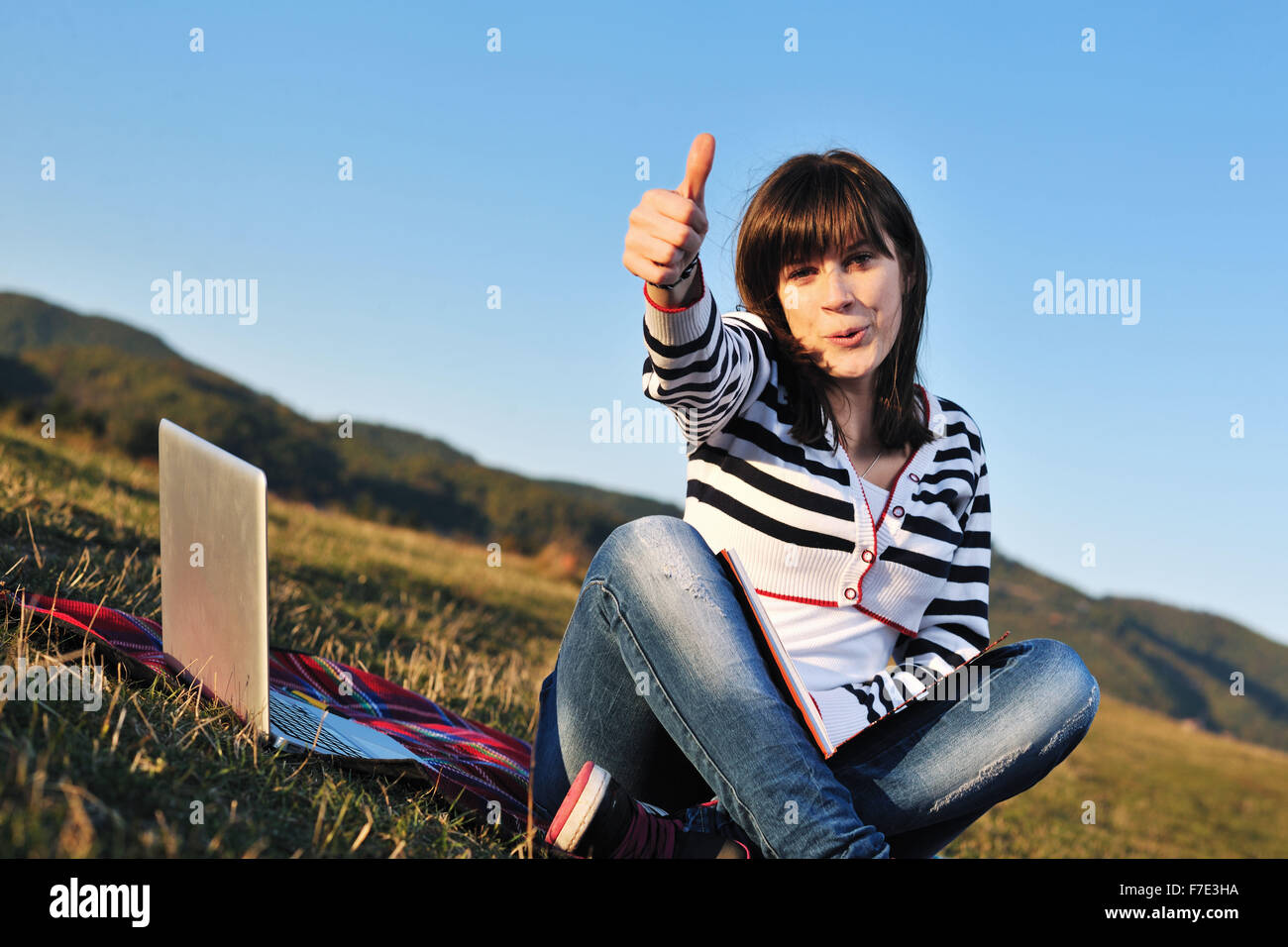 young teen woman work on laptop computer outdoor in nature with blue ...