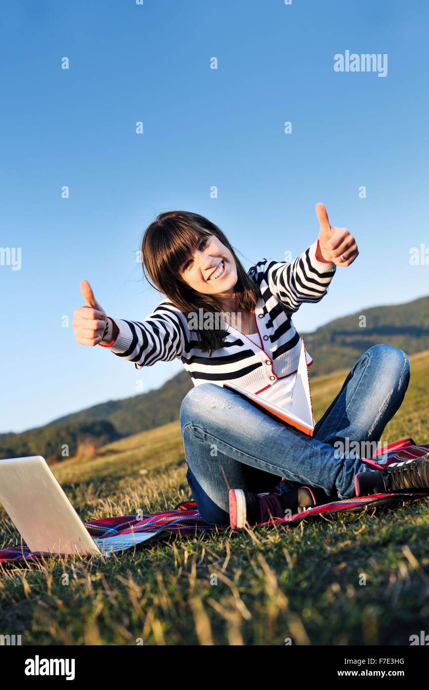 young teen woman work on laptop computer outdoor in nature with blue ...