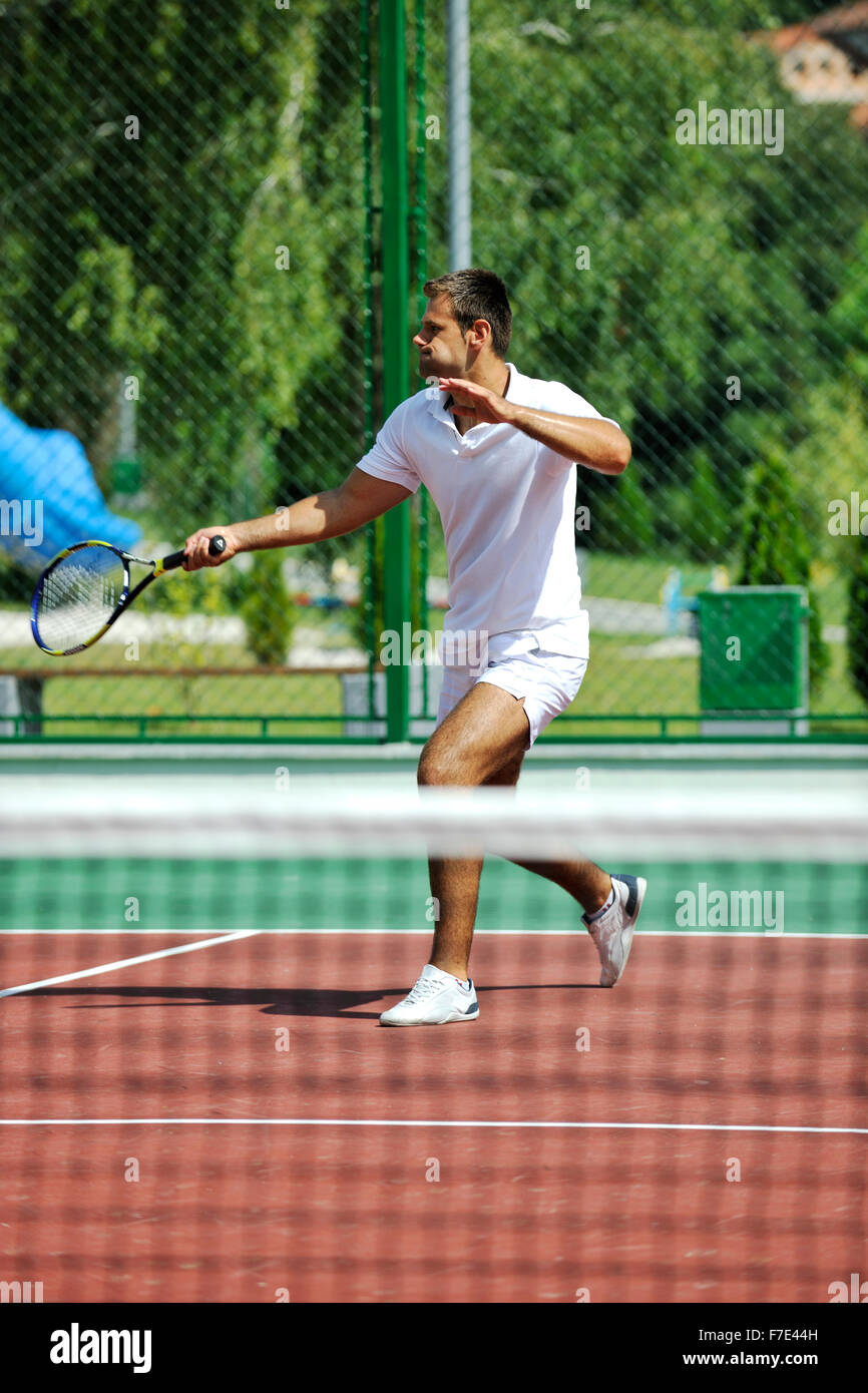 young man play tennis outdoor on orange tennis court at early morning ...