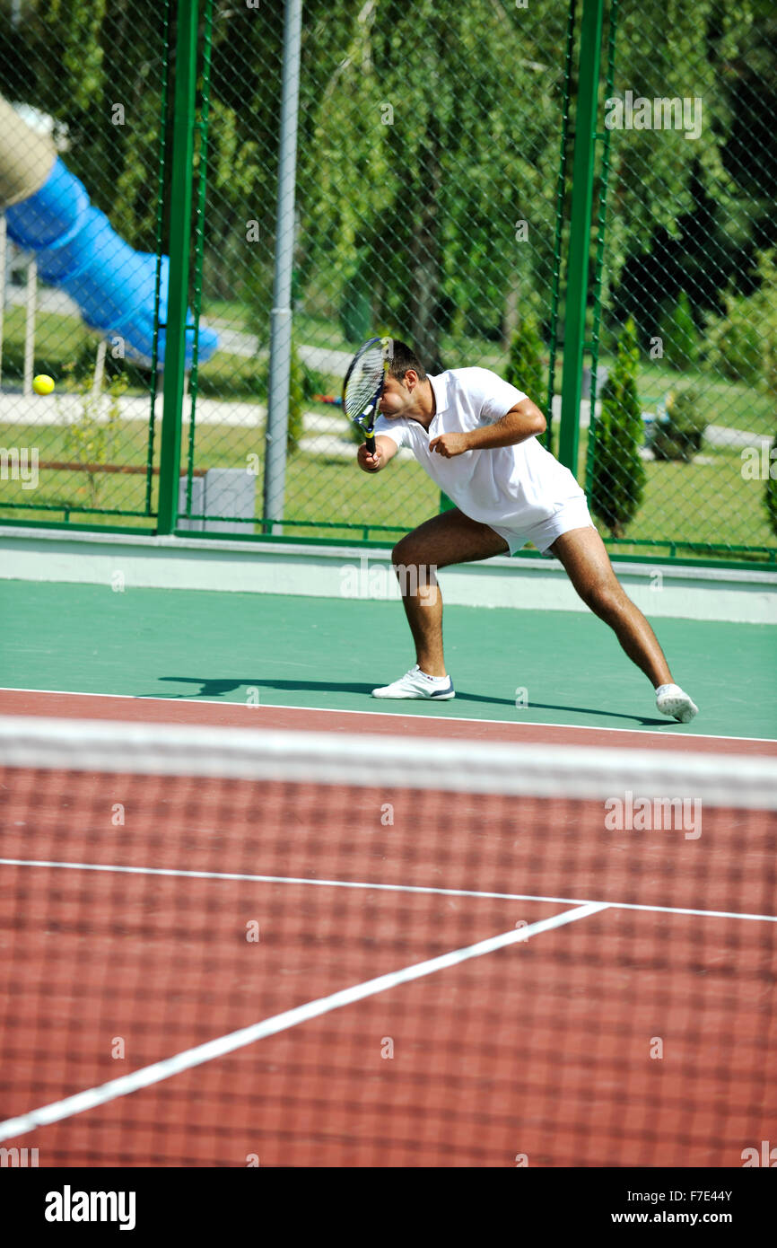 young man play tennis outdoor on orange tennis court at early morning ...