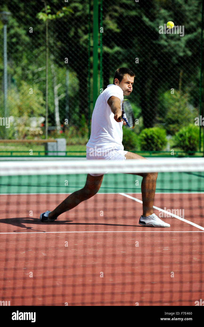 young man play tennis outdoor on orange tennis court at early morning ...